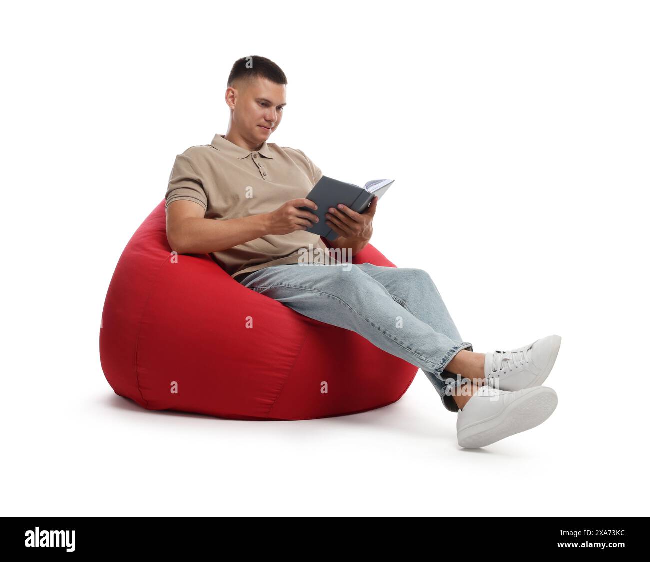 Handsome man reading book on red bean bag chair against white ...