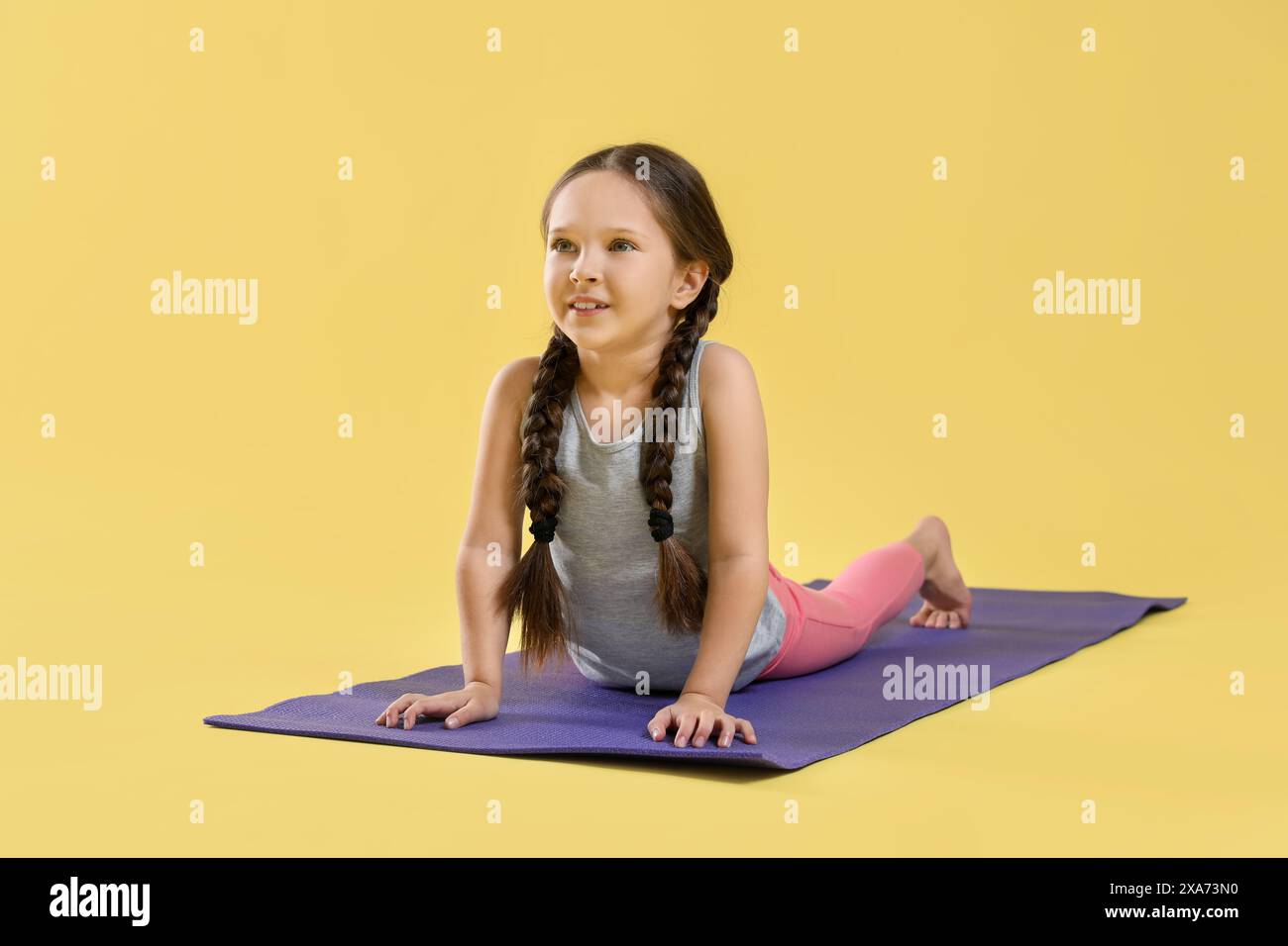 Cute little girl stretching on yellow background Stock Photo - Alamy