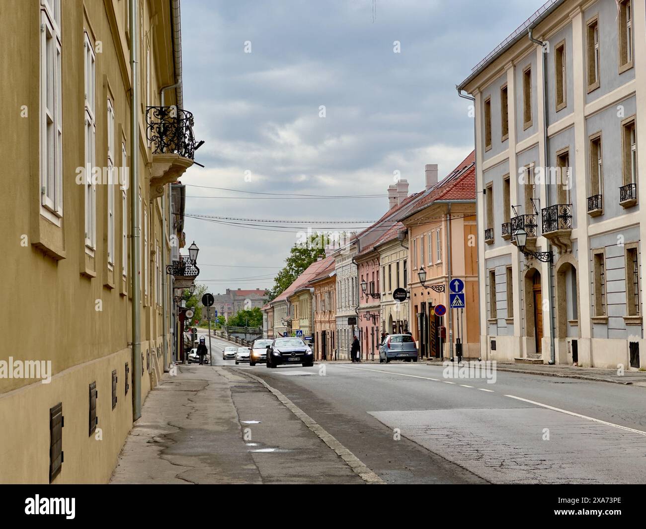 Busy street with multiple vehicles driving past a row of buildings ...