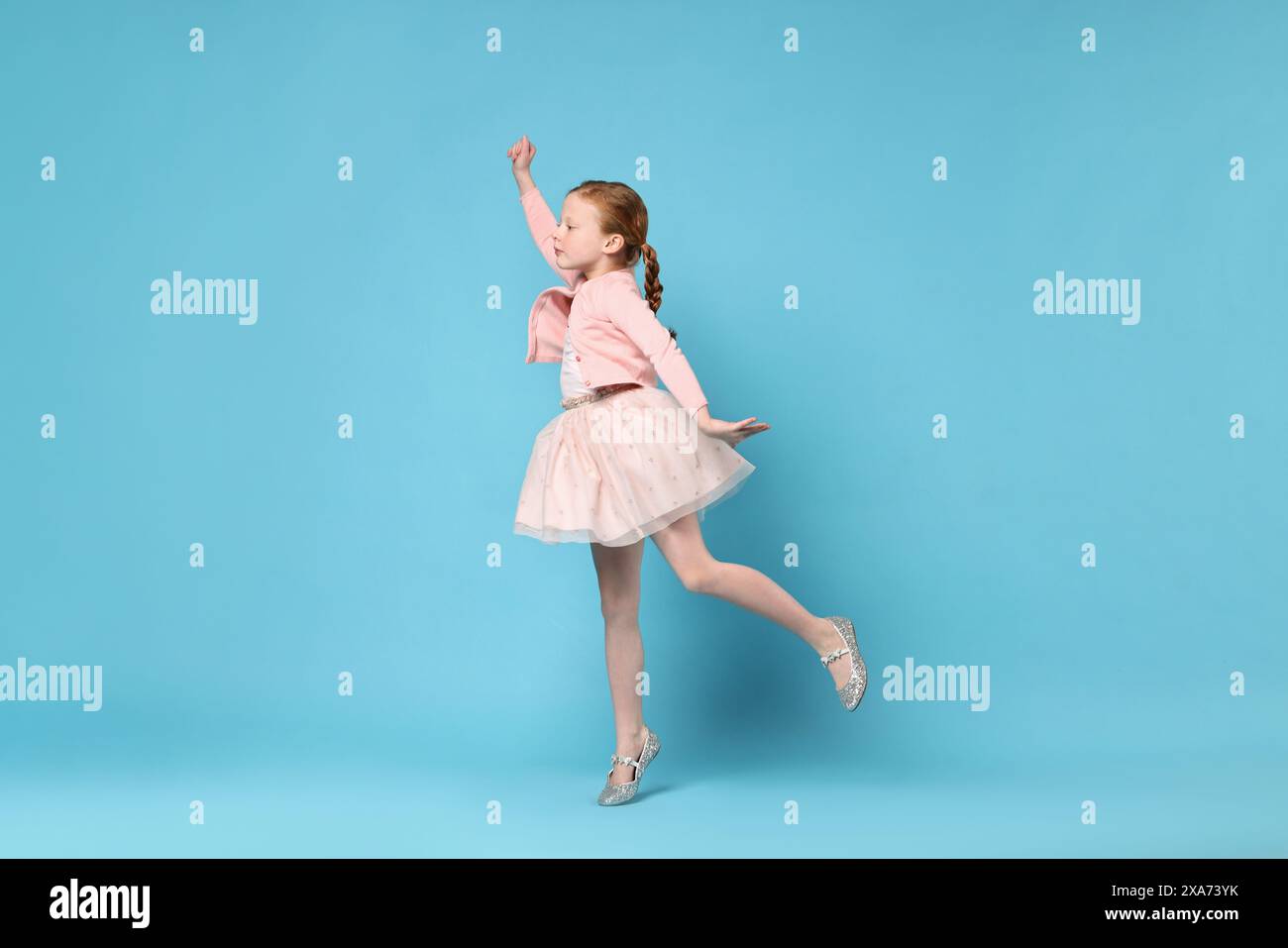 Cute little girl dancing on light blue background Stock Photo - Alamy