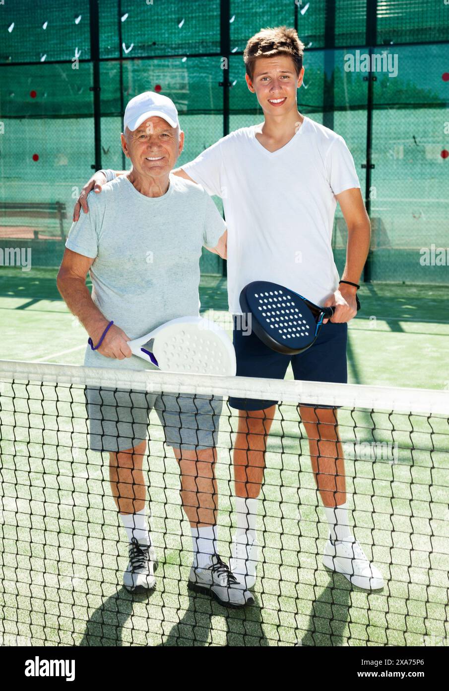 Senior man and young man posing on padel court Stock Photo - Alamy
