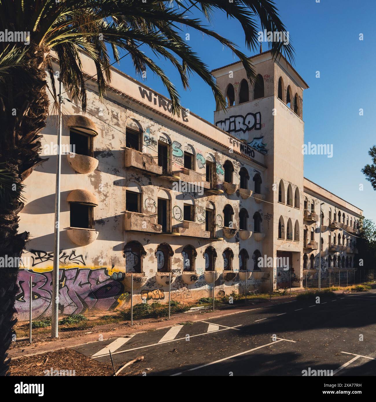 A graffiti-covered wall of an abandoned white building in front of a ...