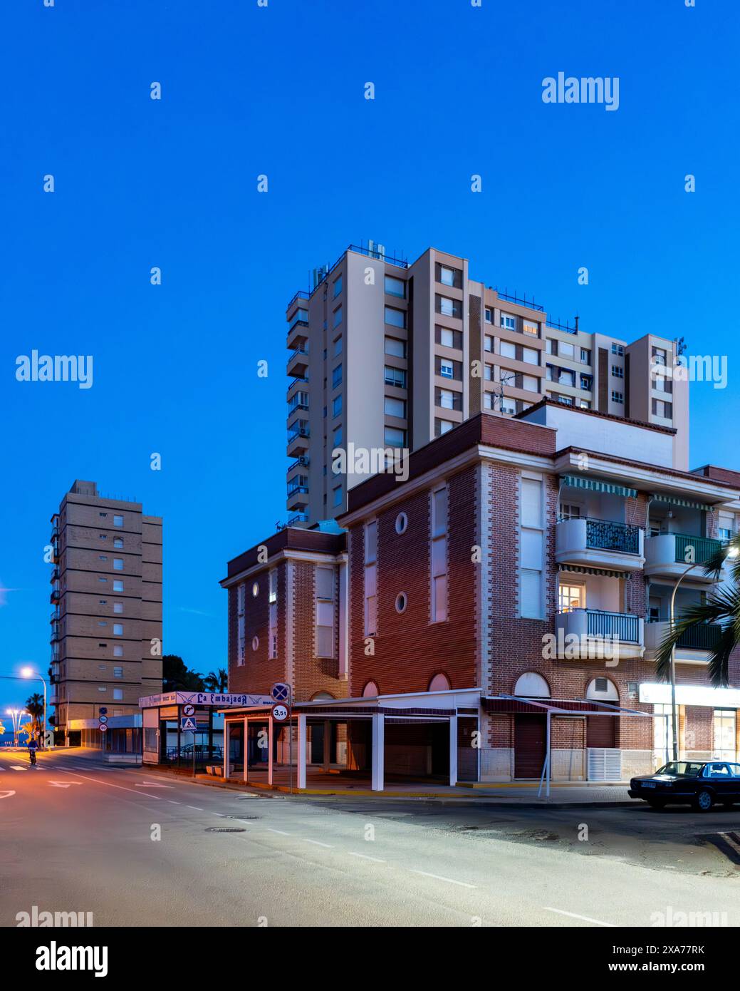 Small city street at night with parked cars on the curb and few ...