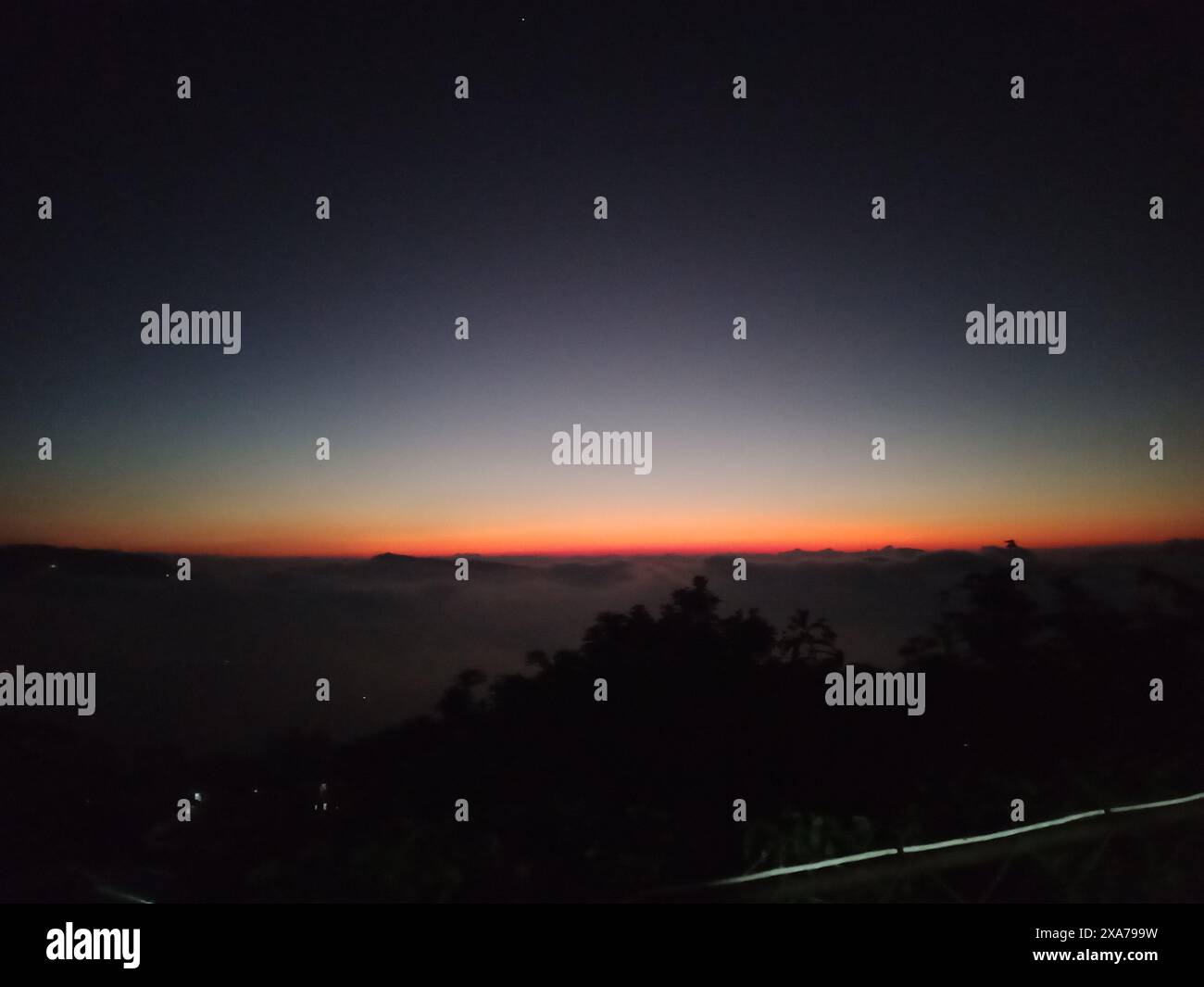A sunrise over a dark landscape with scattered lights and a visible ...