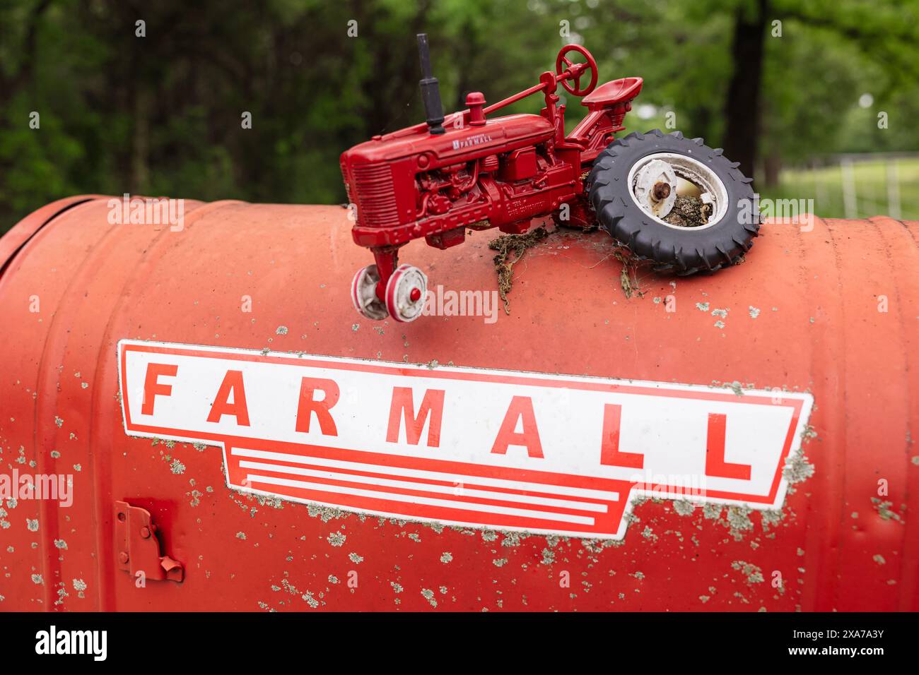 Red vintage tractor on orange barrel beside woodland Stock Photo - Alamy