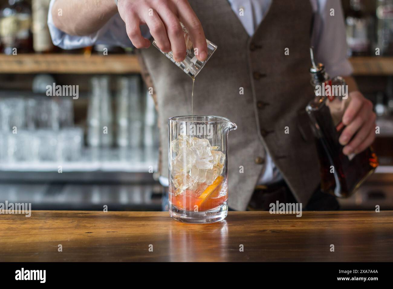 Bartender pouring an ingredient into a mixing glass crafting a whiskey bourbon cocktail Stock ...