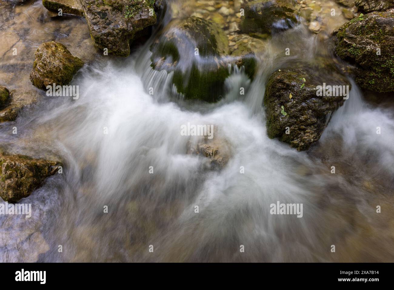 A shot of flowing water over river rocks on the bank Stock Photo - Alamy