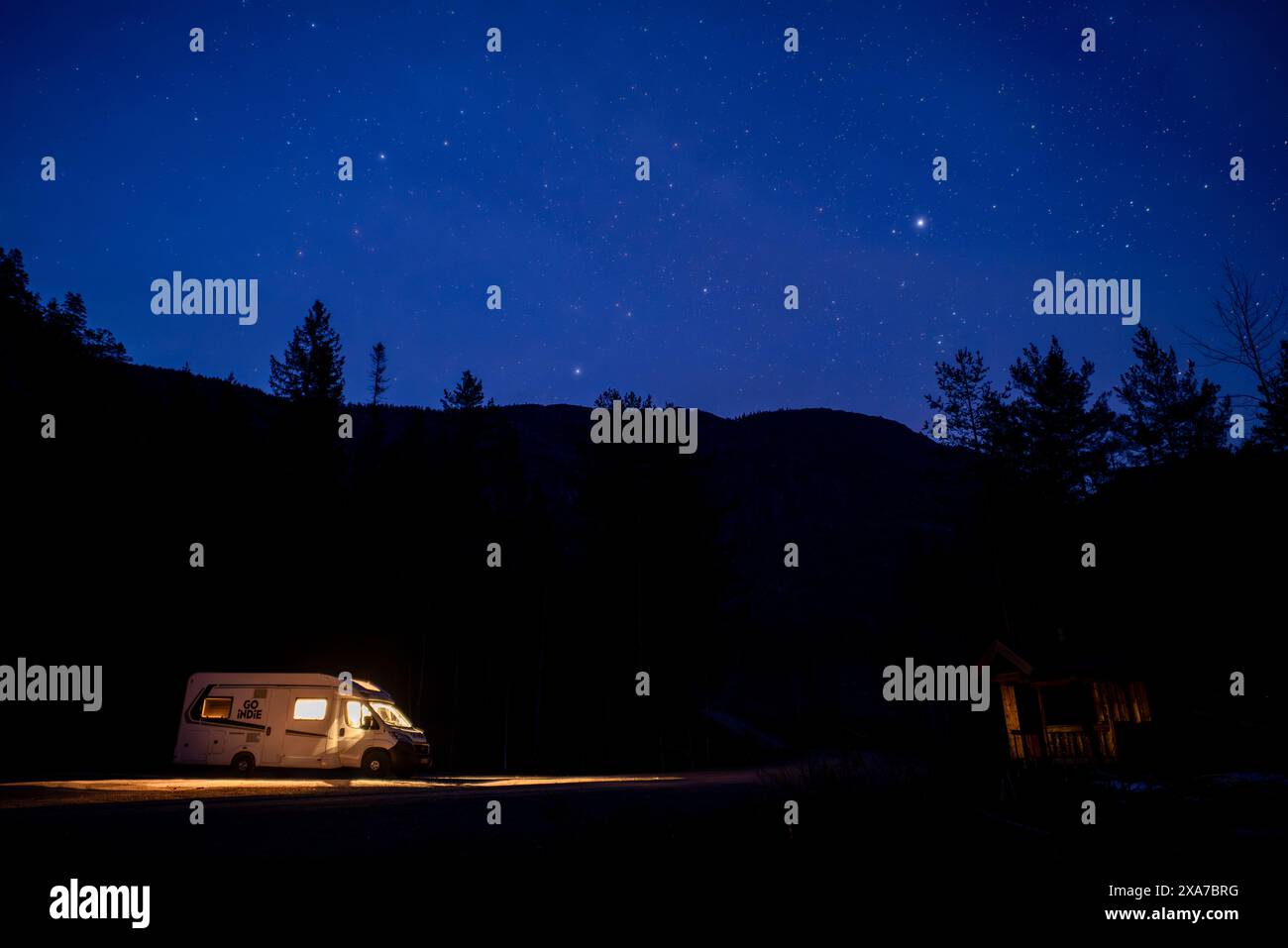 RV parked under starry sky with mountain backdrop Stock Photo - Alamy