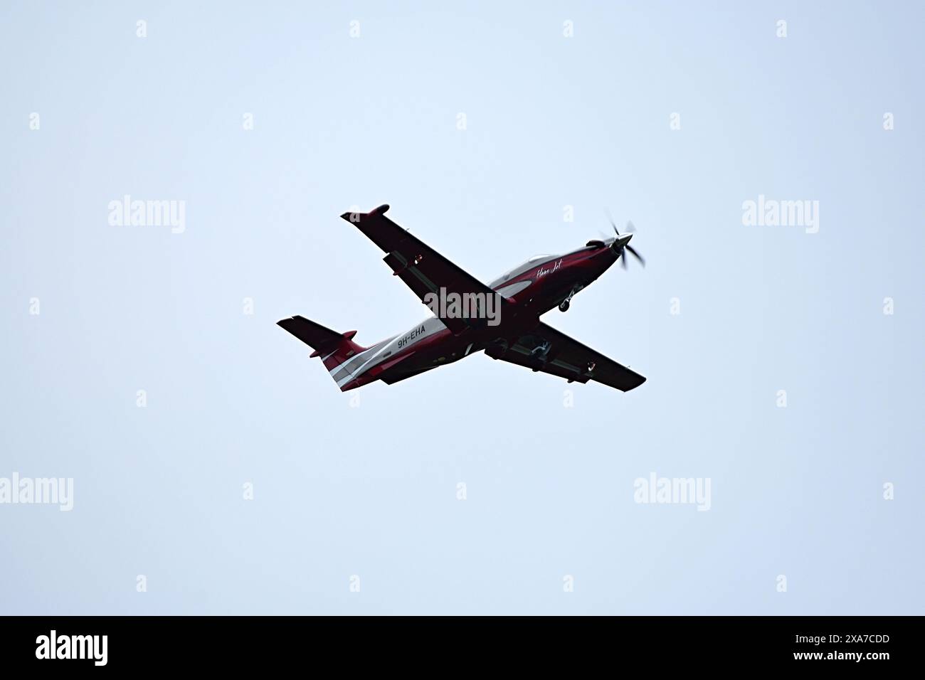 A red and white propeller plane flying in the sky, viewed from below ...