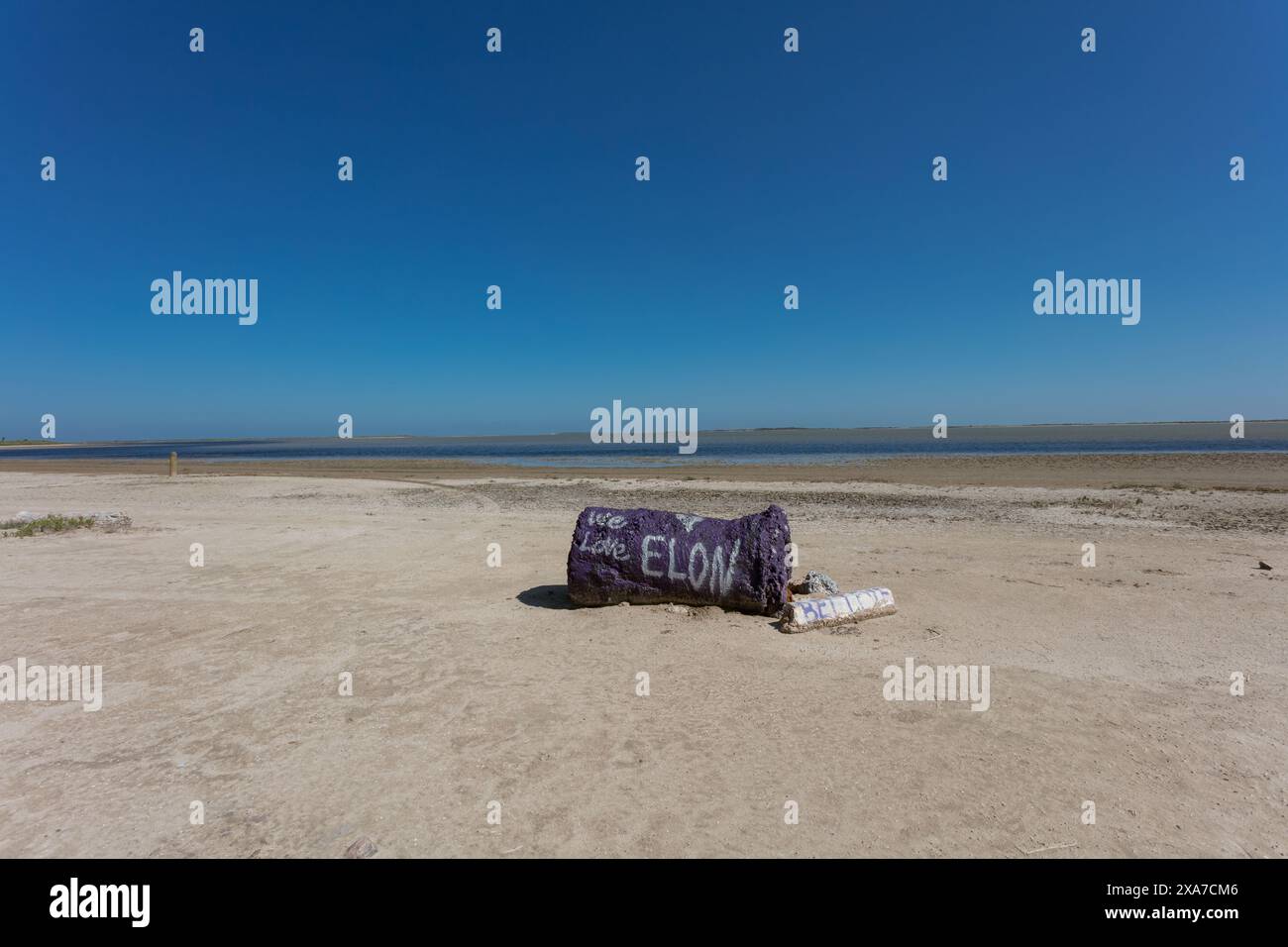A graffiti-painted barrel on the beach with the name ELON written on it ...