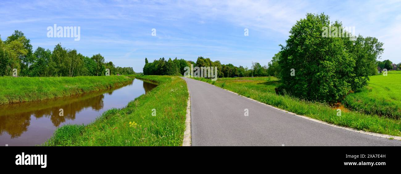 A panoramic view of a serene riverside cycle path, bordered by lush ...