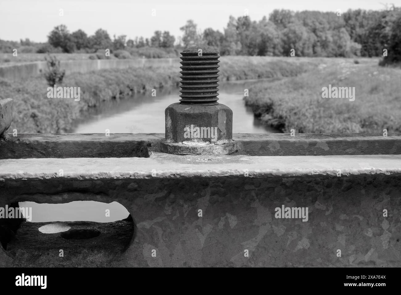 A monochrome close-up of a sizable bolt and nut on an aged bridge ...