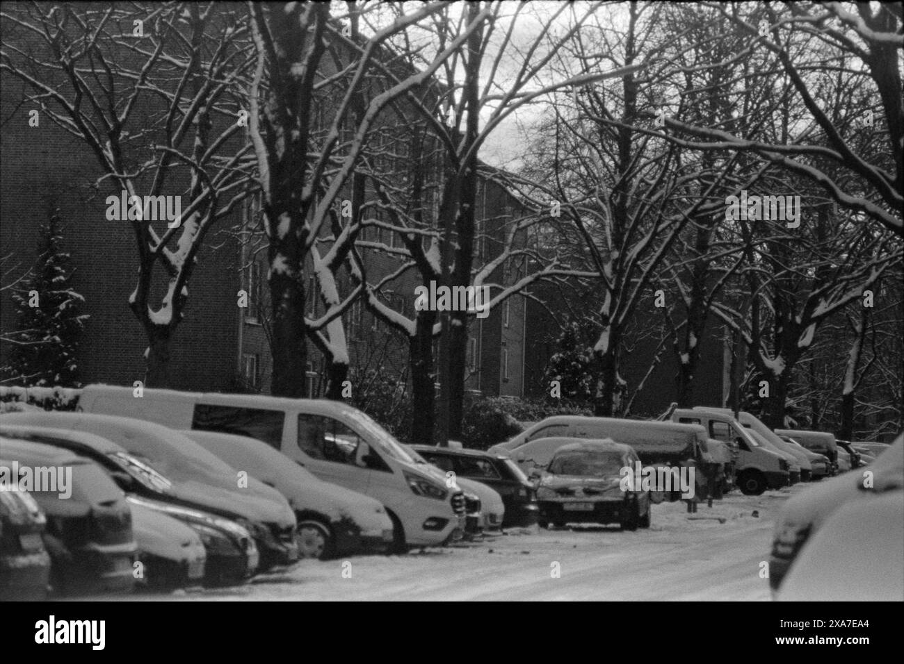 A monochrome image of several cars parked together in a snowy setting ...