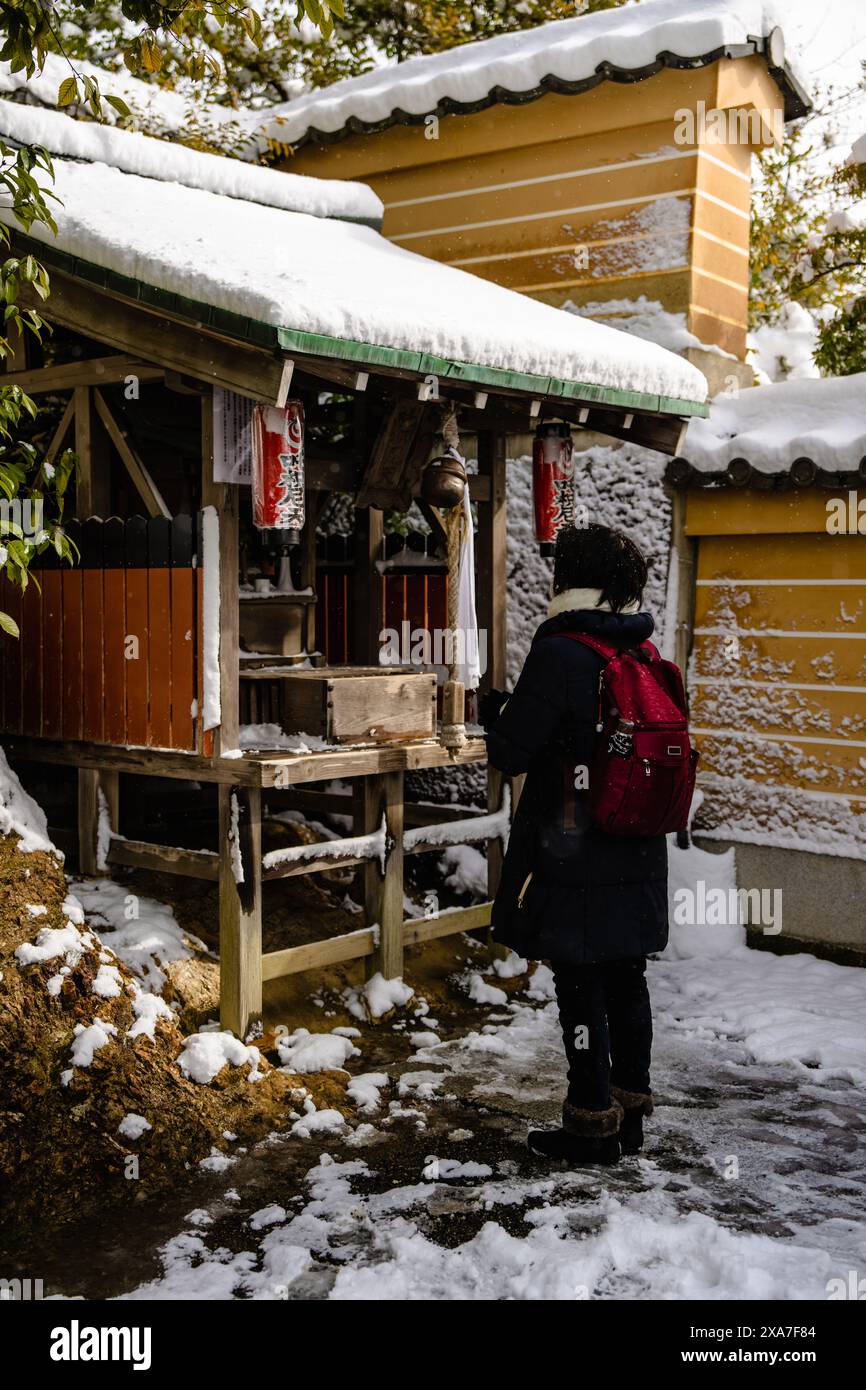 A woman enters a snowy building to view an outdoor shrine Stock Photo ...