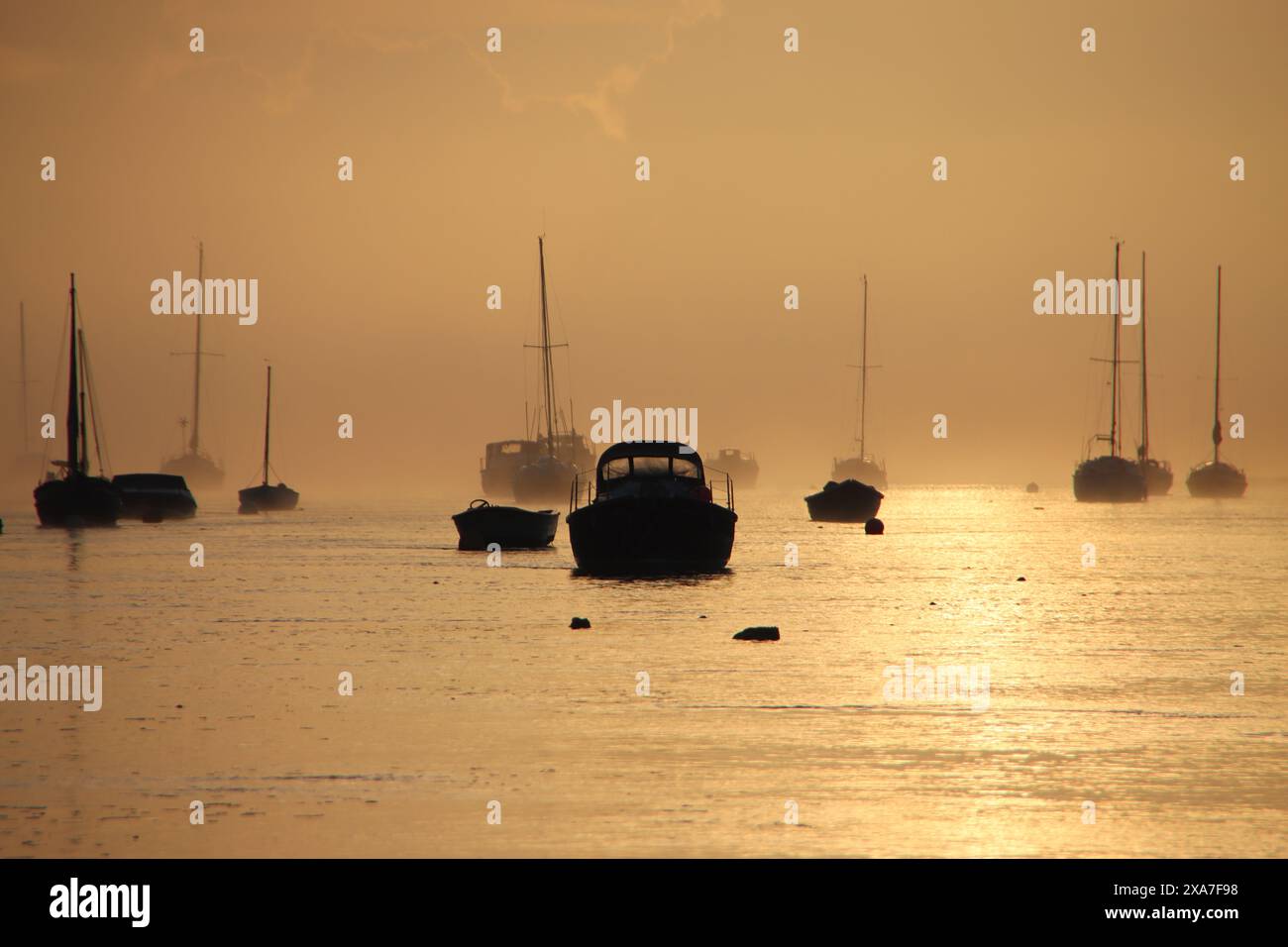 Multiple boats on water as the sun sets at dawn Stock Photo - Alamy