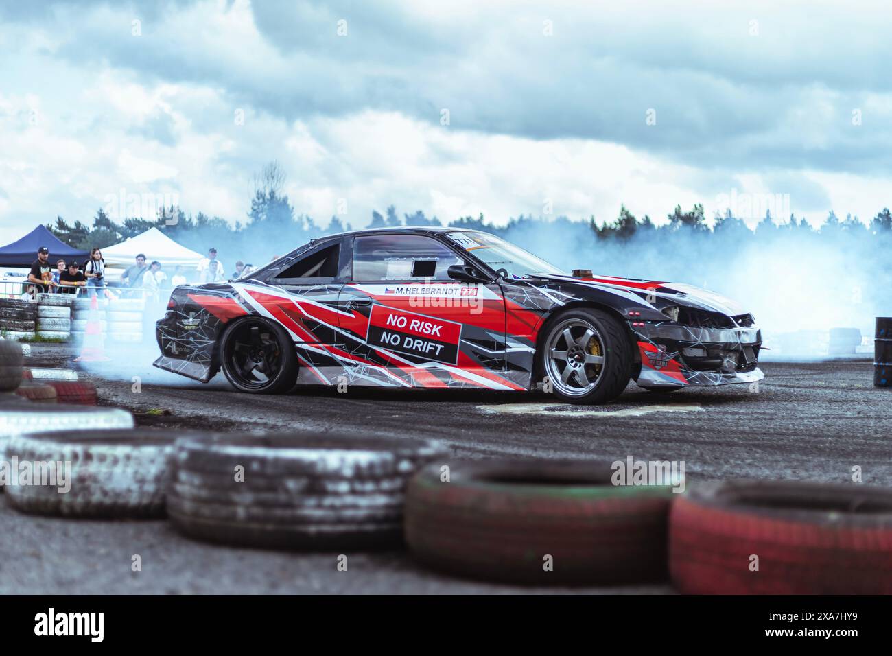 A race car with red and white stripes making a turn and emitting smoke ...