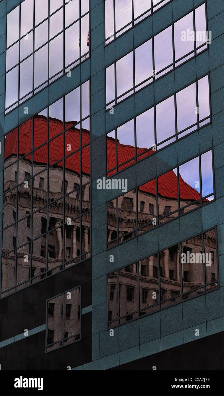 A glass modern building reflecting an older terracotta-roof building ...