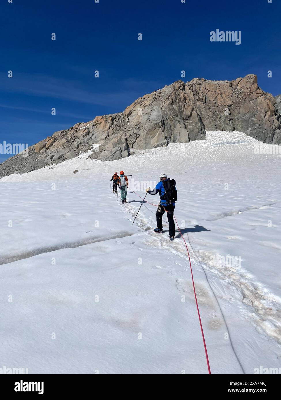 Two hikers ascending snowy mountain slope with poles in France Alps ...