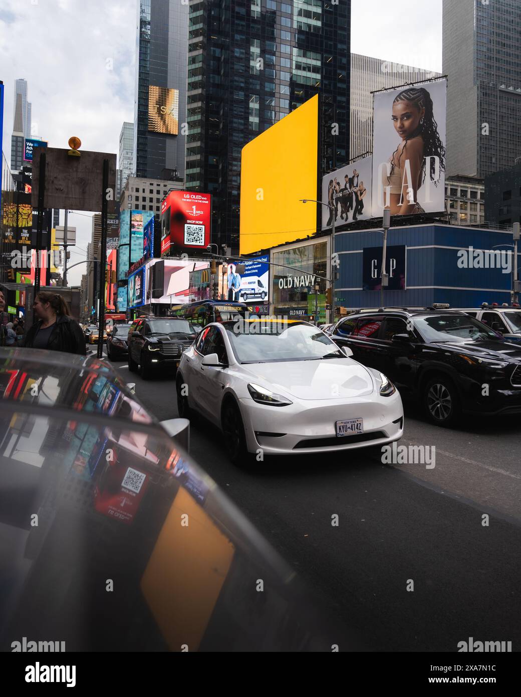 A white Tesla car navigating traffic in Times Square, New York City ...