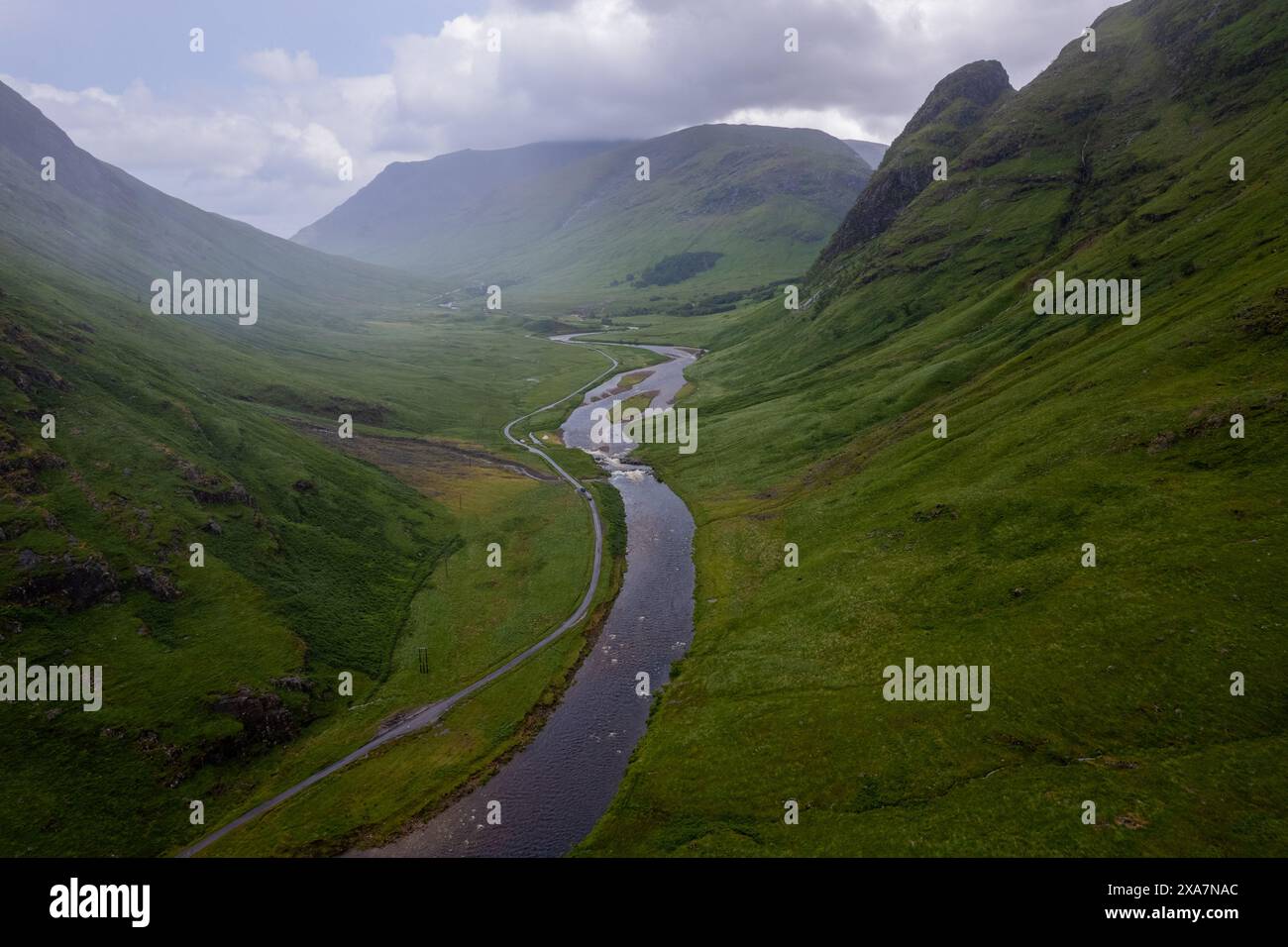 A winding road meandering through lush green mountains and rivers Stock ...