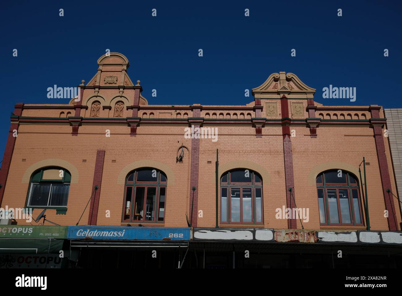 Painted Victorian facade, brick building with arched windows and scroll ...