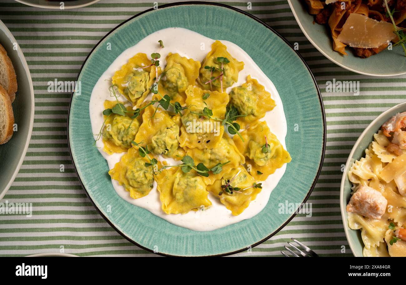 Italian ravioli with spinach and cheese on blue plate serving at table ...