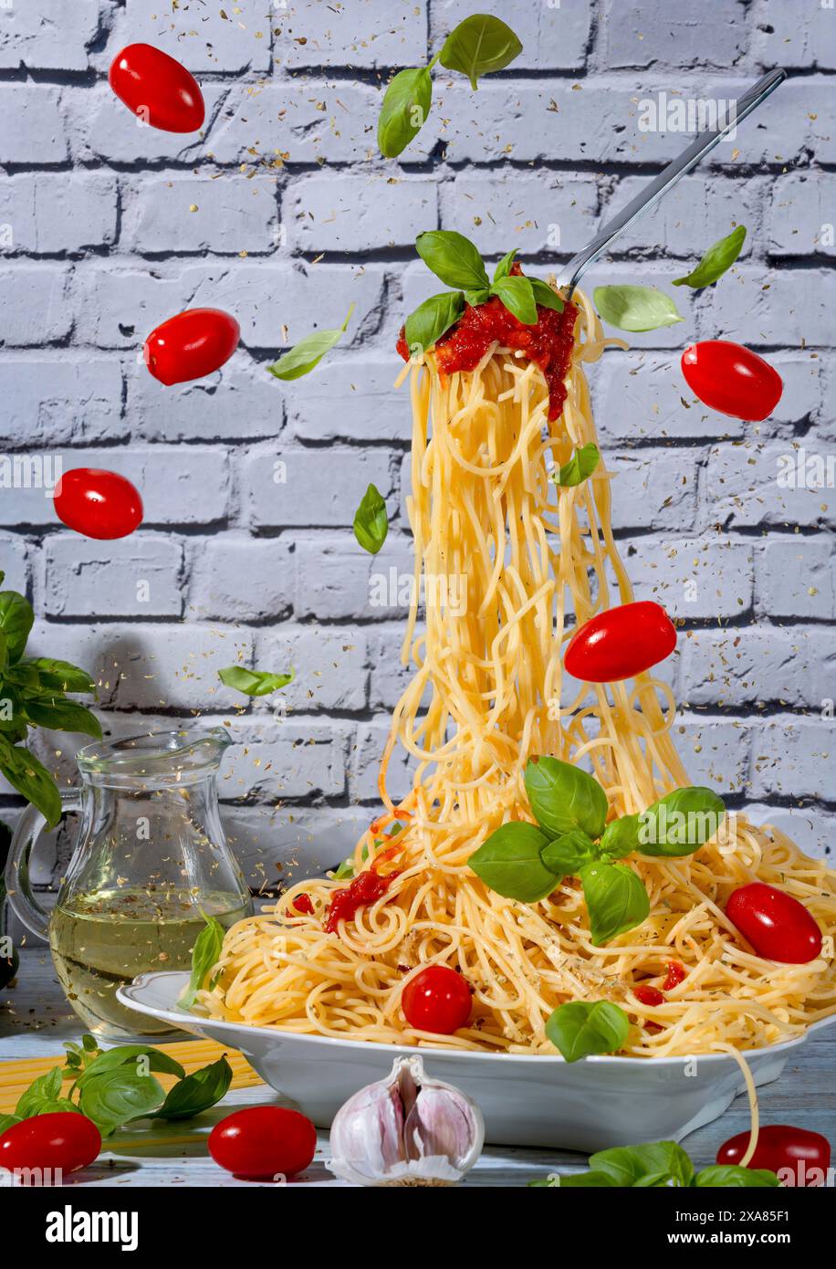 Spaghetti in a bowl and on a floating fork surrounded by tomatoes ...