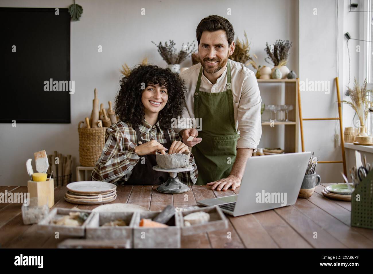 Happy couple creating pottery art in studio with laptop Stock Photo - Alamy