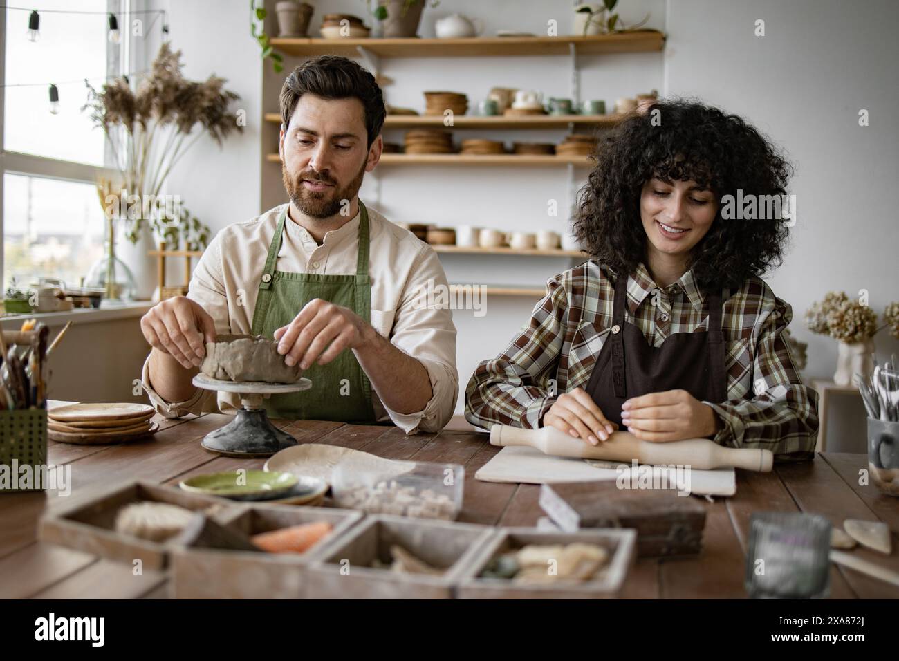 Man and woman sculpting clay together in pottery workshop Stock Photo ...