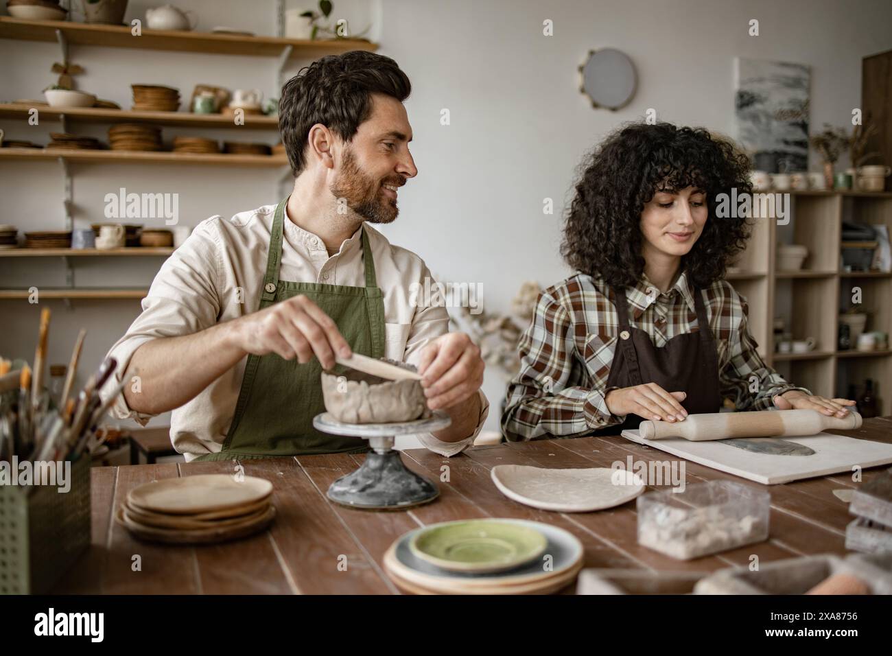 Couple sculpting clay together during pottery workshop in studio Stock ...