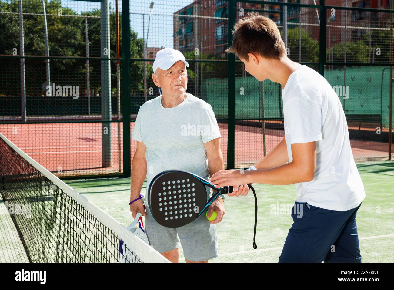 Padel players of different generations talking on court playing paddle ...