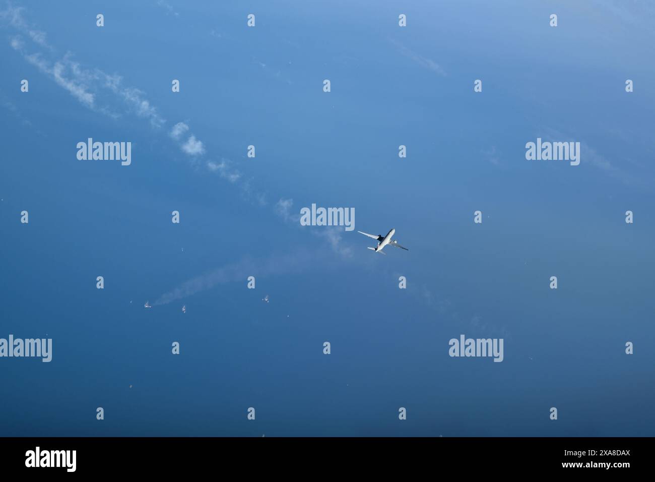 Boeing 777 airplane Flying Over Blue Ocean with Small Boats Below Stock ...