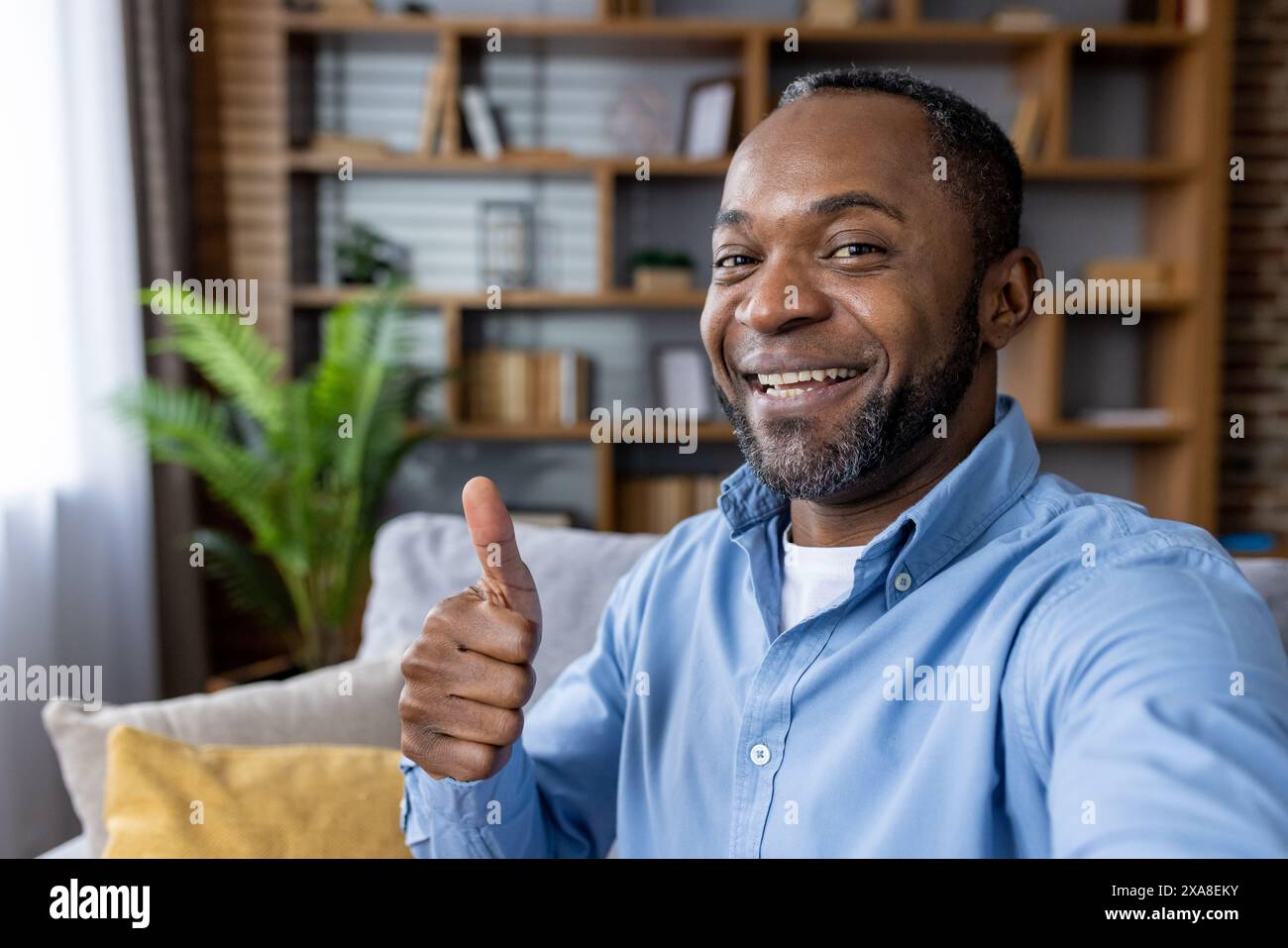Happy man in blue shirt giving a thumbs up gesture while on a video ...