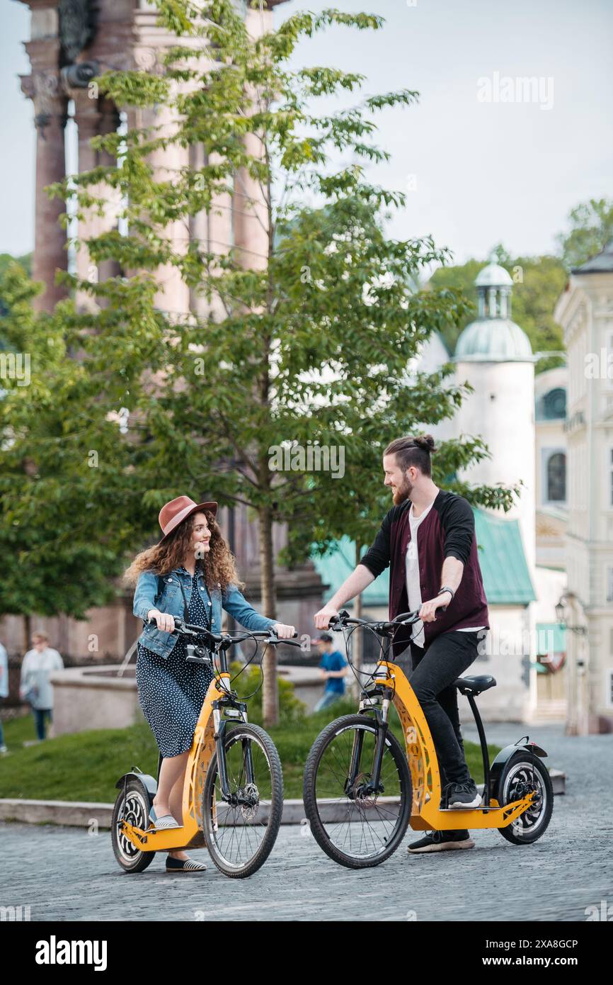 Travellers couple on electric scooters in small city, sightseeing ...