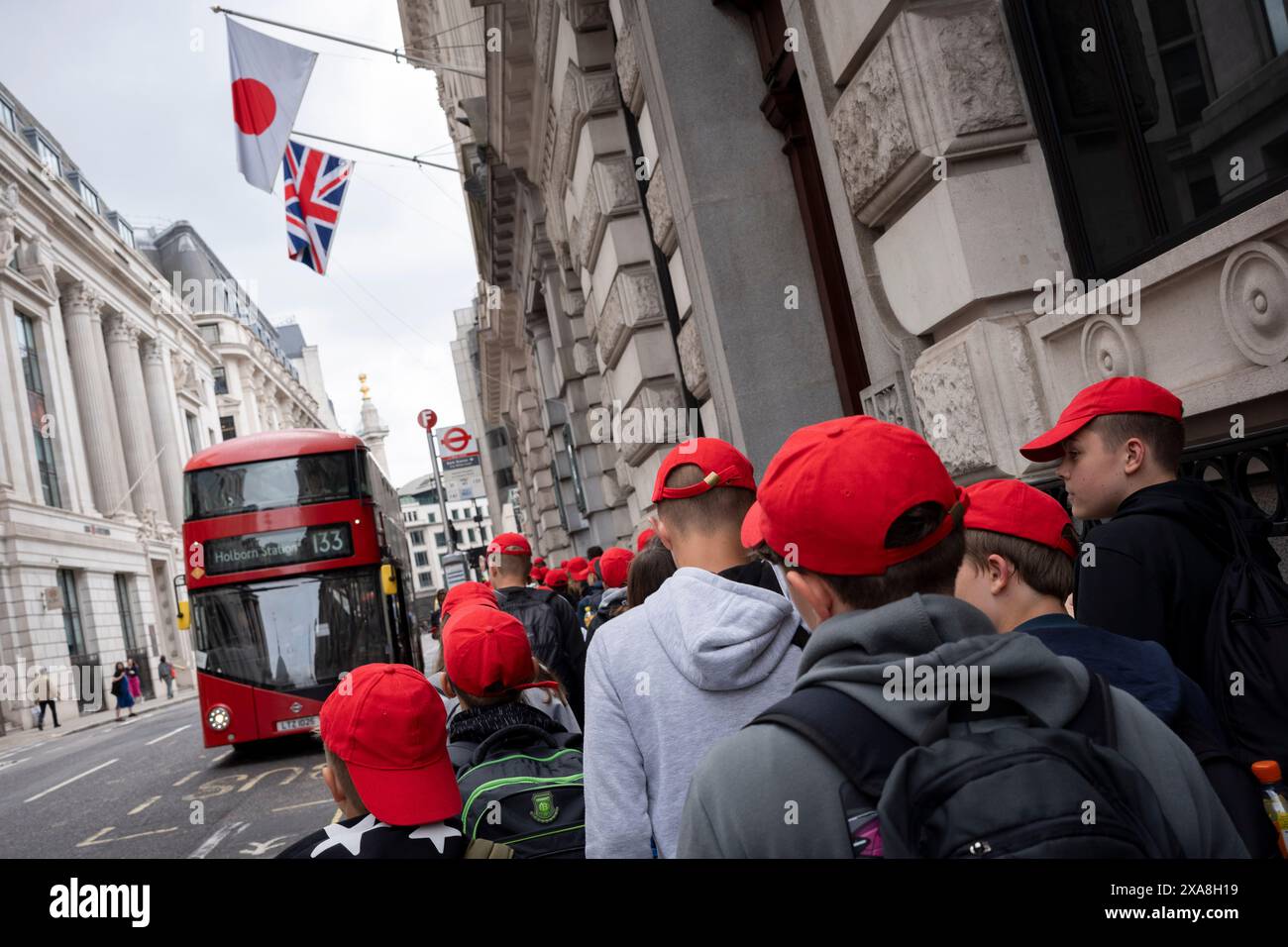 A group of foreign schoolboys wearing red caps, walk beneath the ...