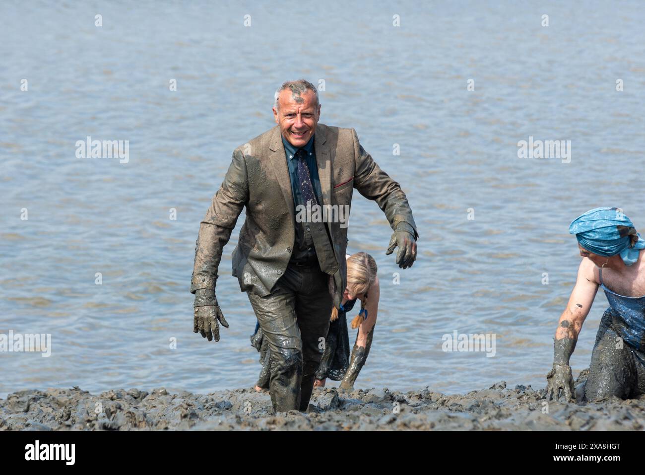 People taking part in the Maldon Mud Race in Maldon, Essex, UK, in the mud of the River Chelmer ...