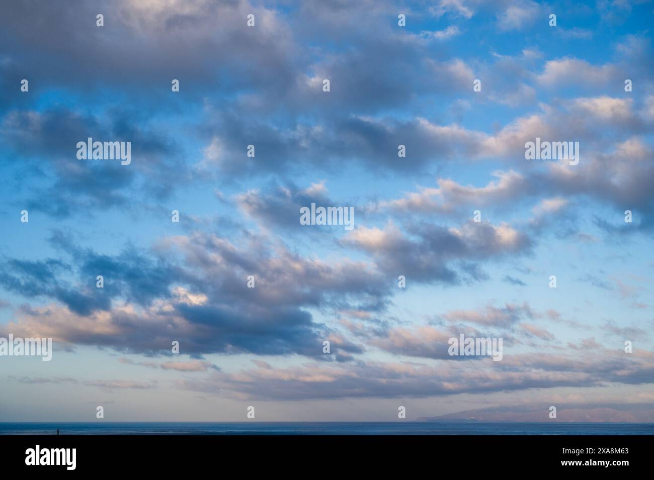 The sky is cloudy and the ocean is calm. The clouds are scattered throughout the sky, creating a ...