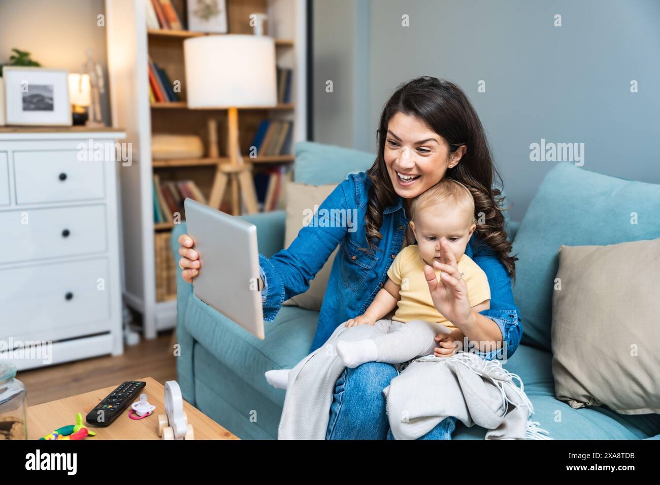 Happy family mom and kid daughter using digital tablet sitting on sofa ...