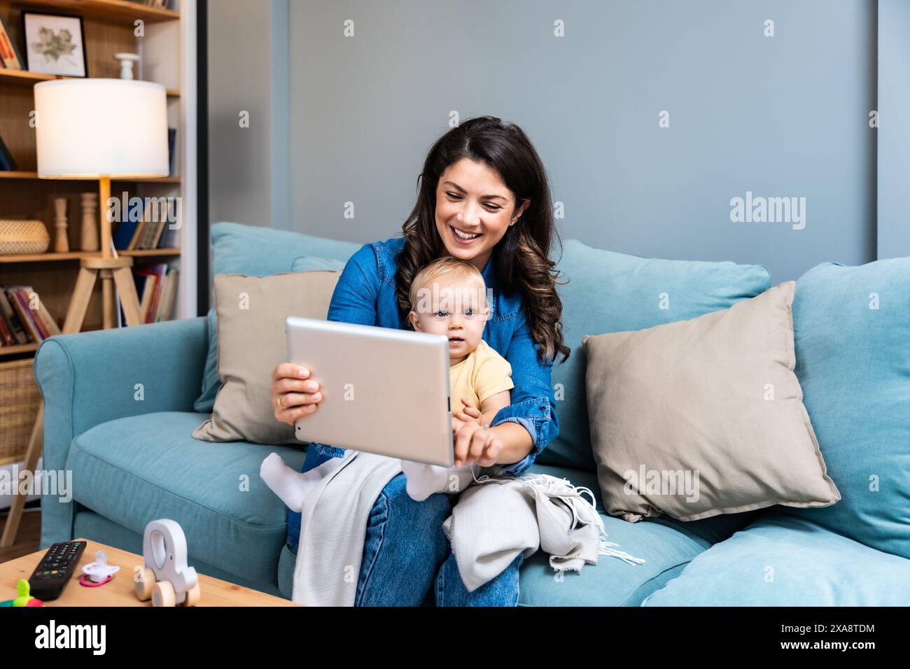 Happy family mom and kid daughter using digital tablet sitting on sofa ...