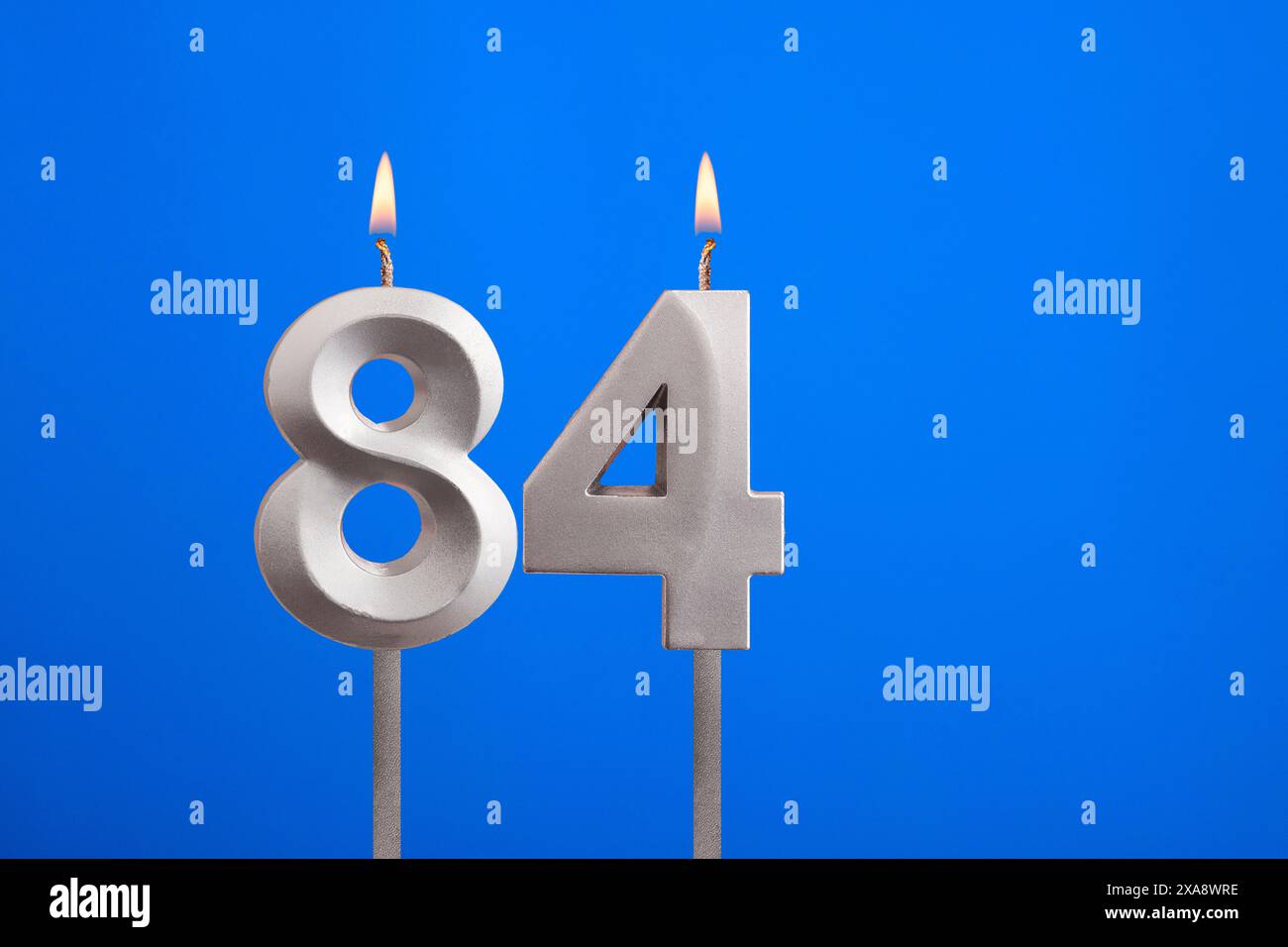 Birthday number 84 - Candle lit on blue background Stock Photo - Alamy