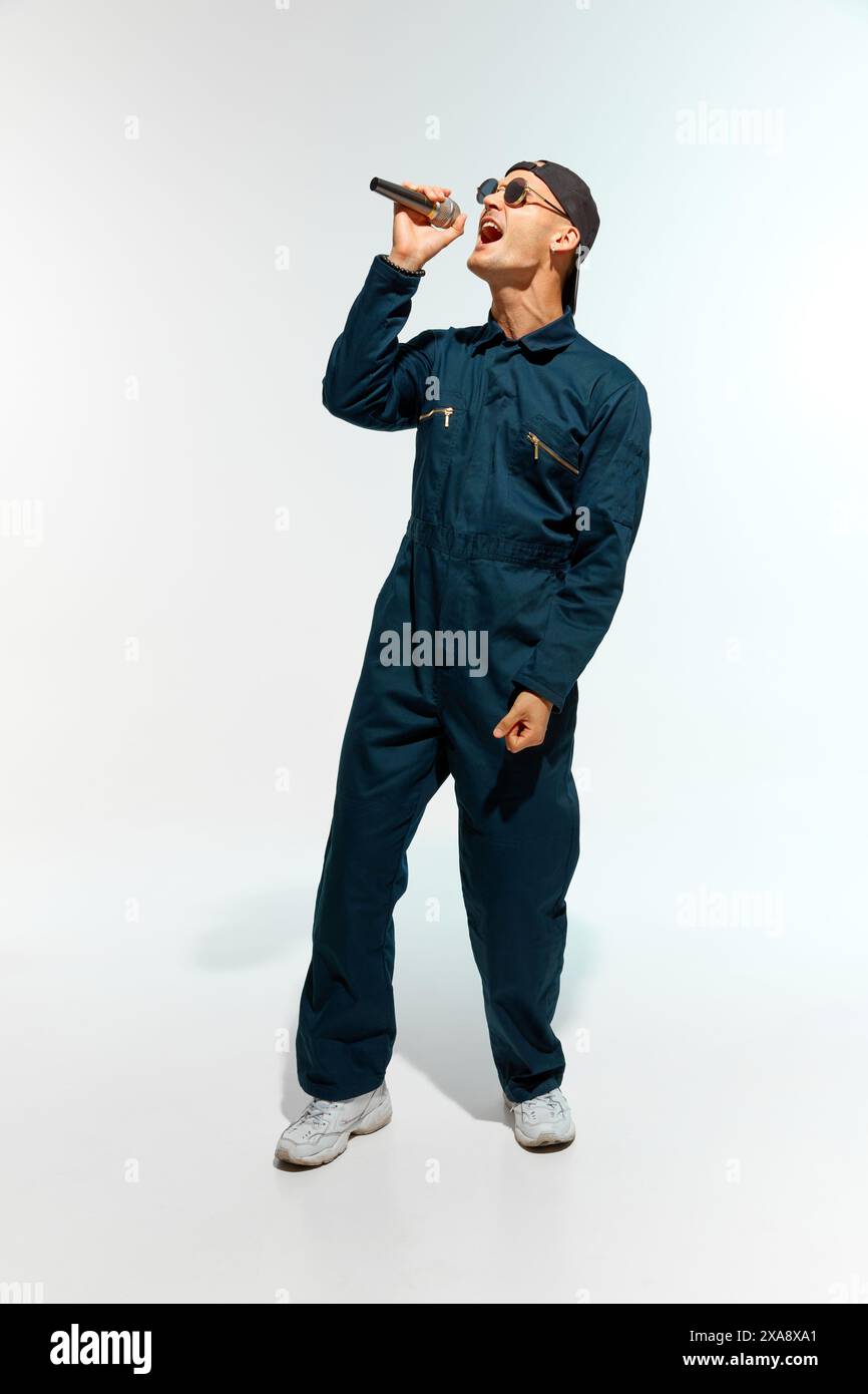 Artistic young man, musician dressed overalls with sunglasses singing ...