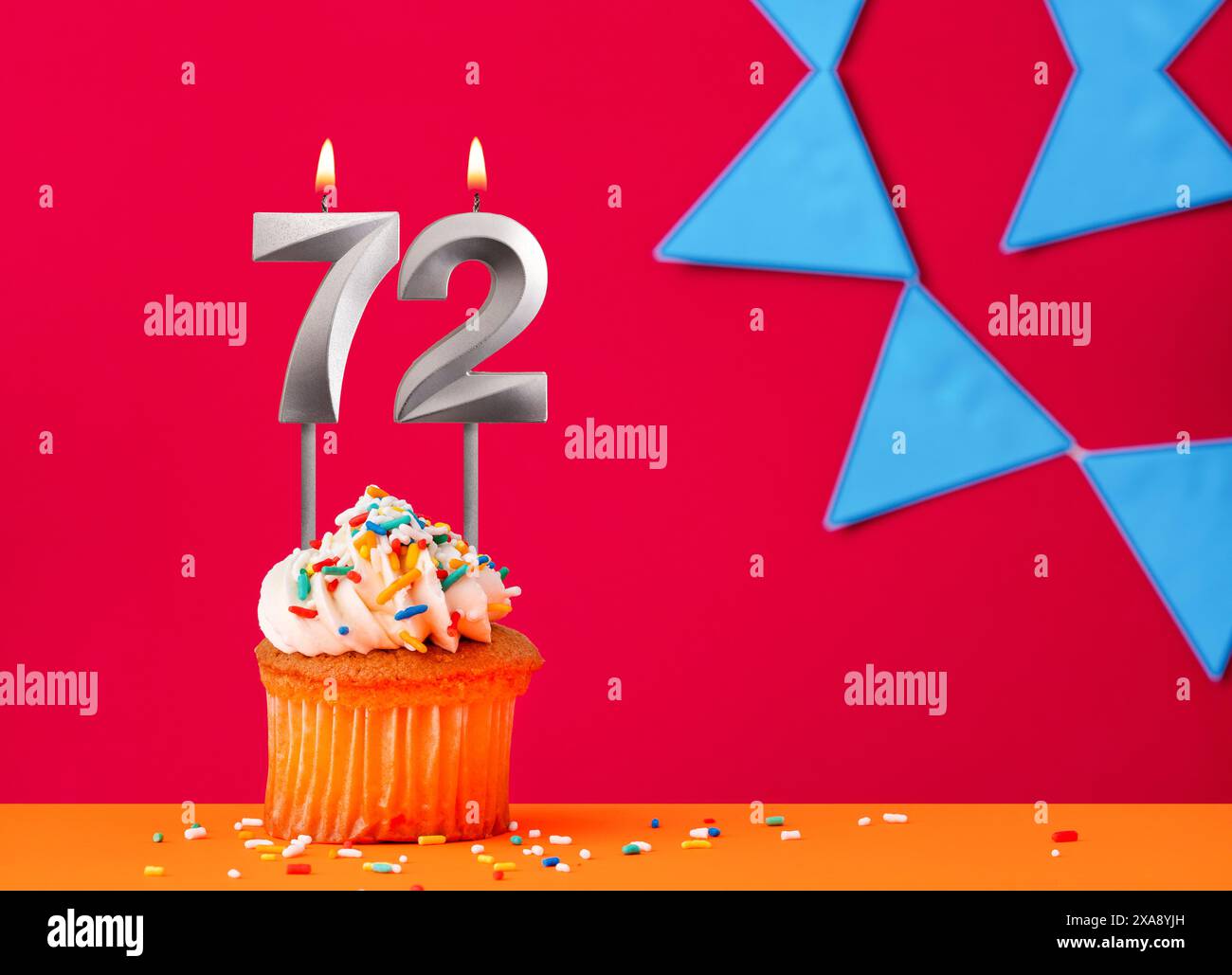 Birthday cupcake with candle number 72 on a red background with blue ...