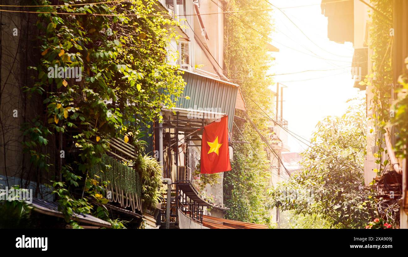 A vibrant red Vietnamese national flag waves prominently on a balcony ...