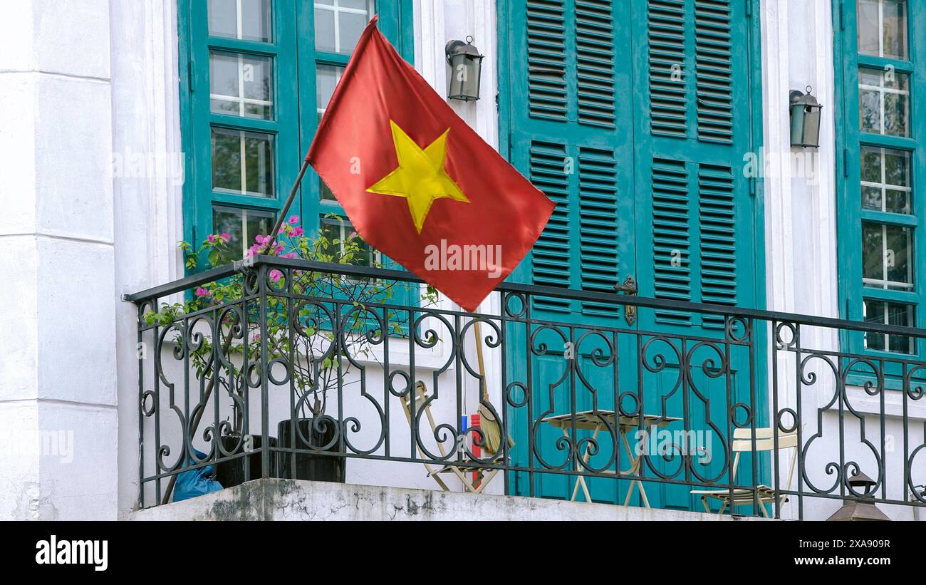 A vibrant red Vietnamese national flag waves prominently on a balcony ...