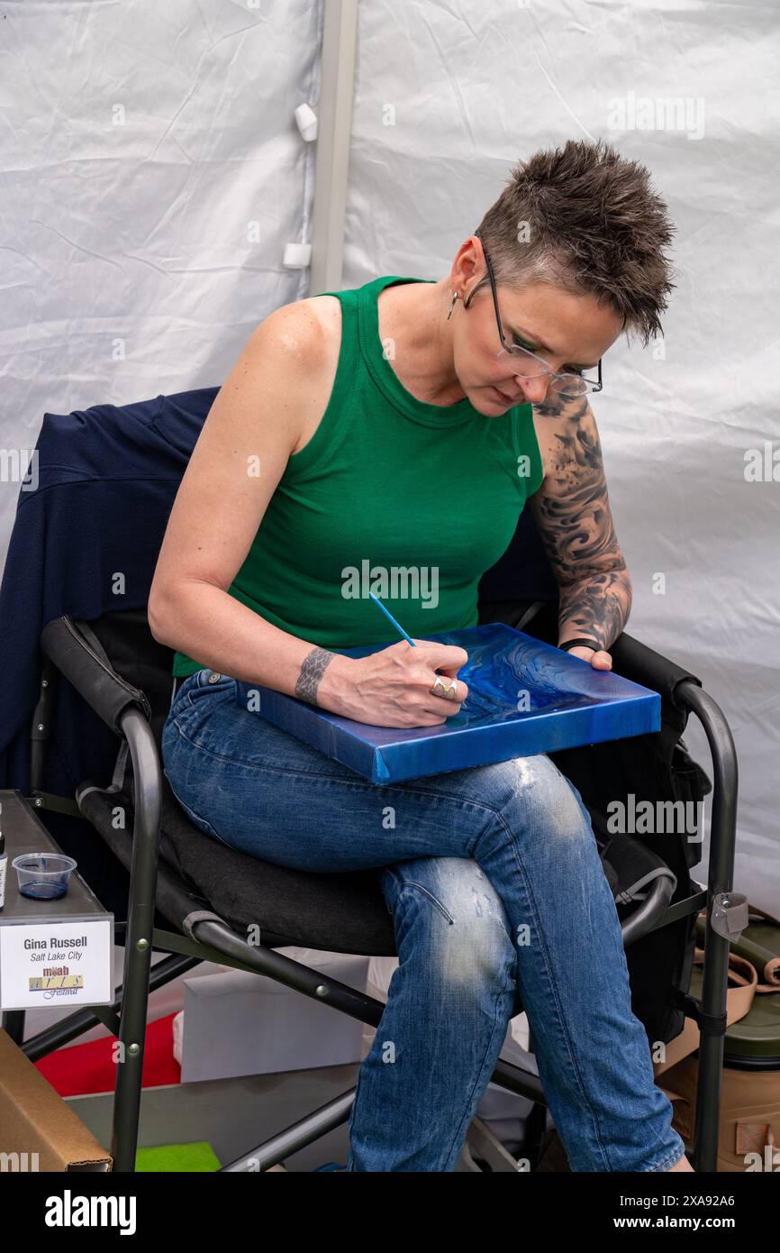 An artist works on a painting at the annual Moab Arts Festival in Moab ...