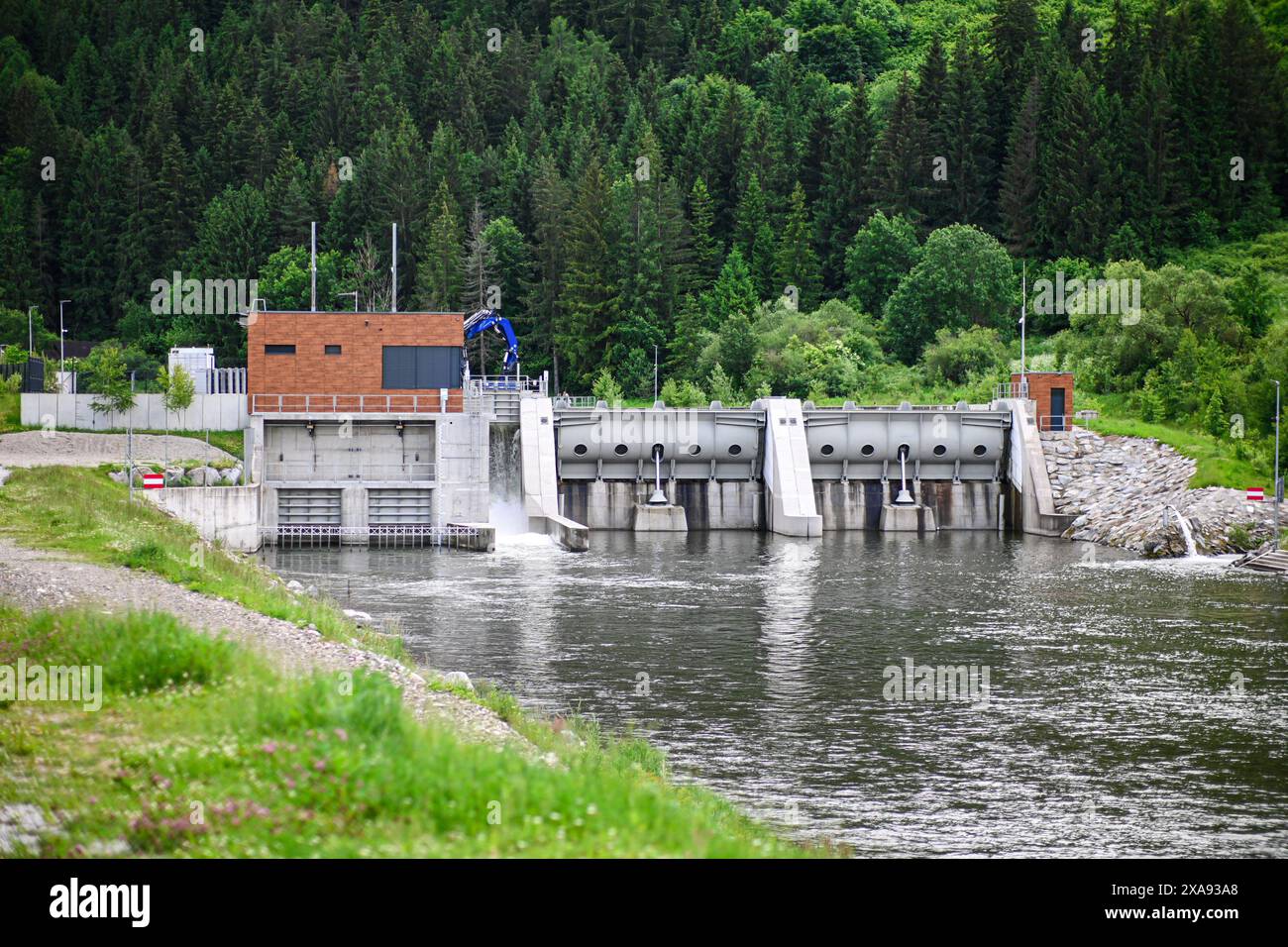 Small hydroelectric dam operates in a forested area, exemplifying ...