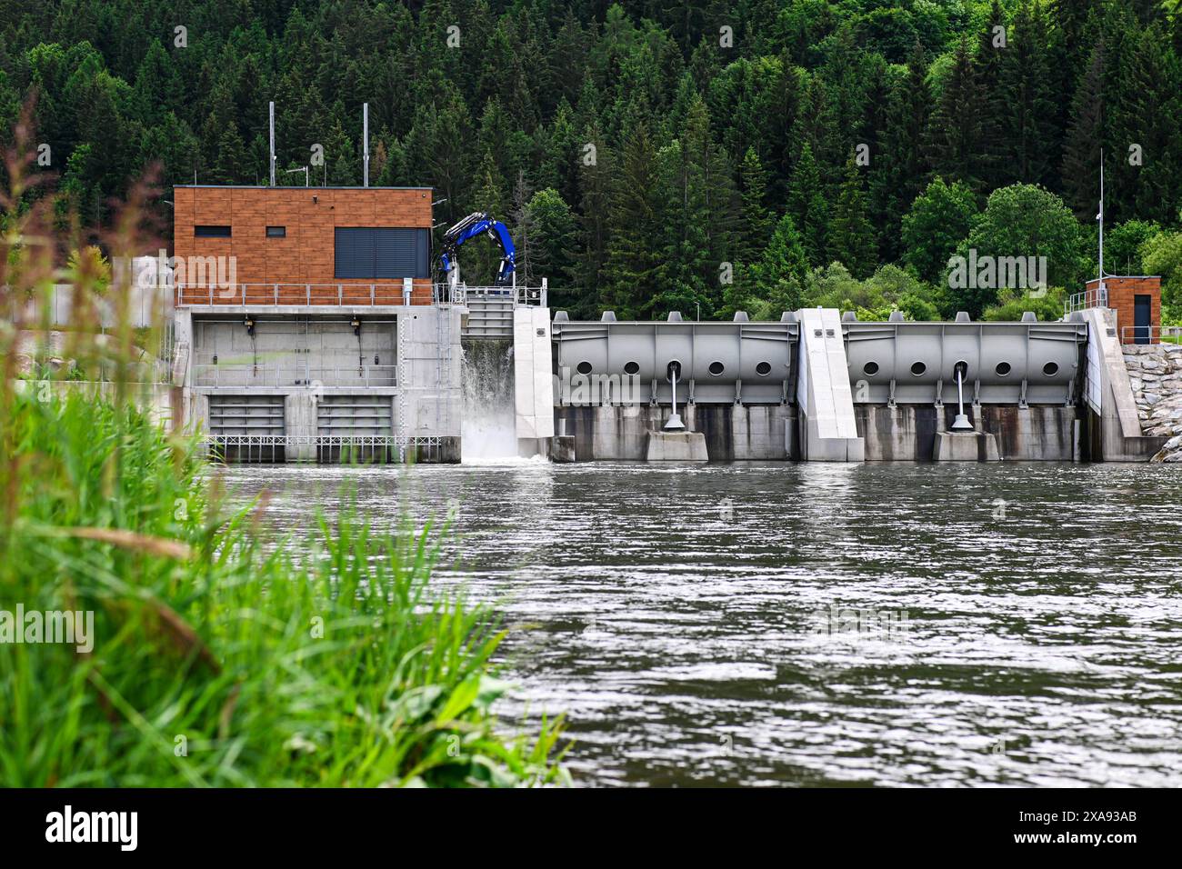 Small hydroelectric dam operates in a forested area, exemplifying ...