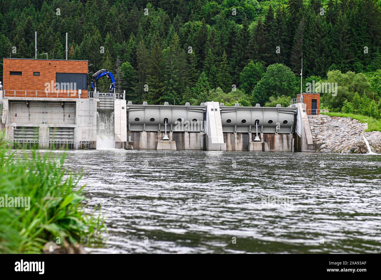 Small hydroelectric dam operates in a forested area, exemplifying ...