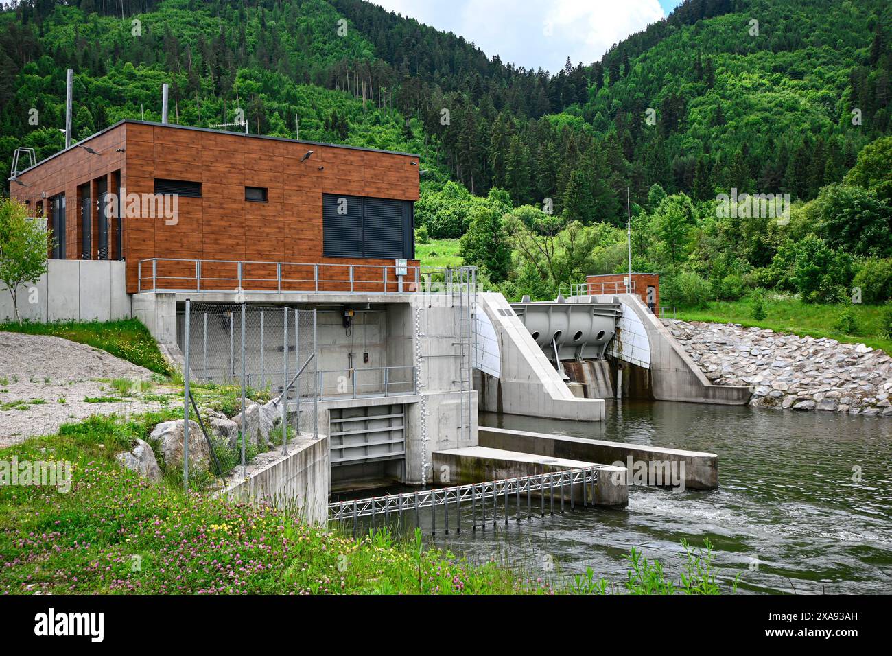 Small hydroelectric dam operates in a forested area, exemplifying ...