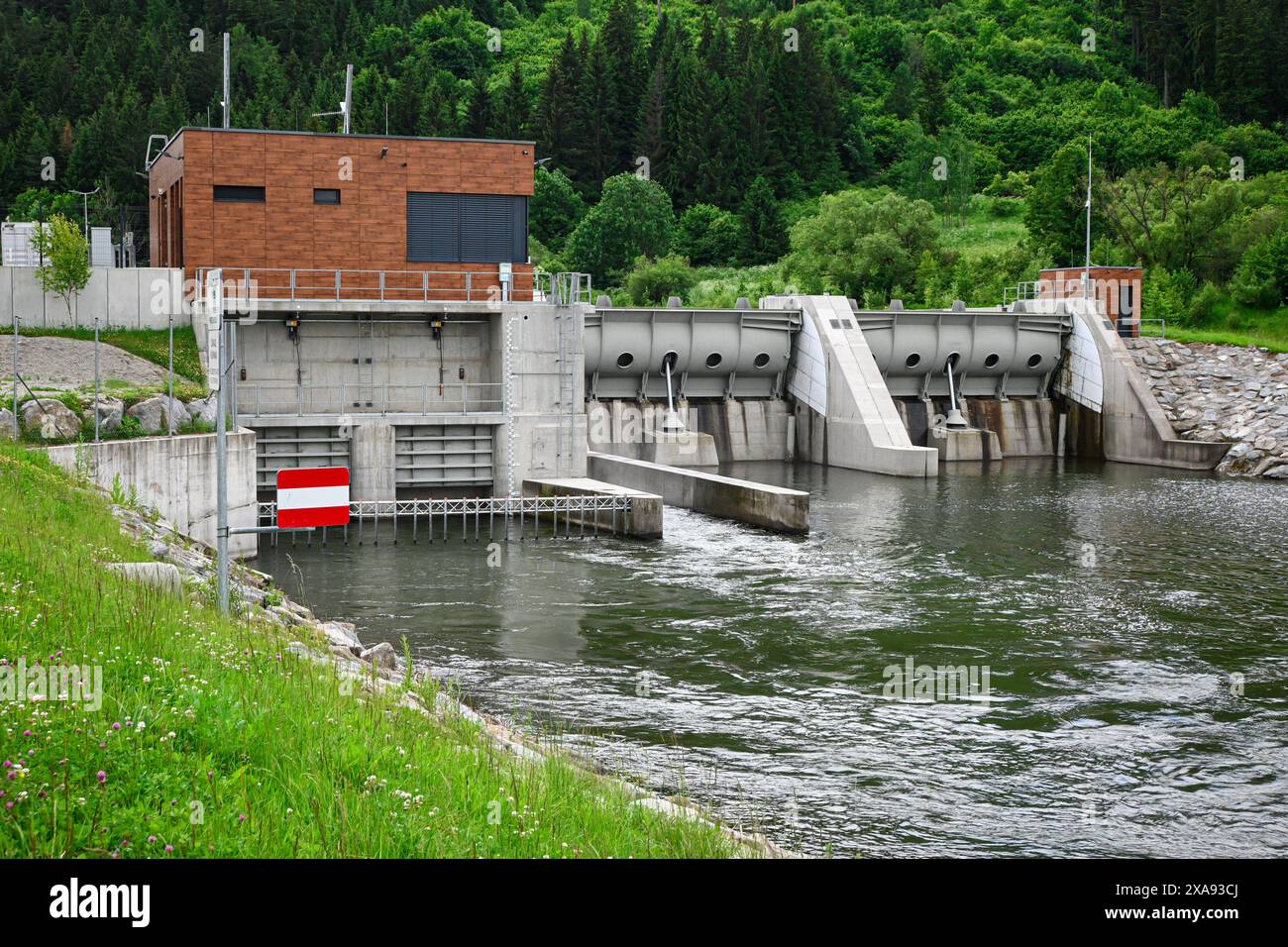 Small hydroelectric dam operates in a forested area, exemplifying ...